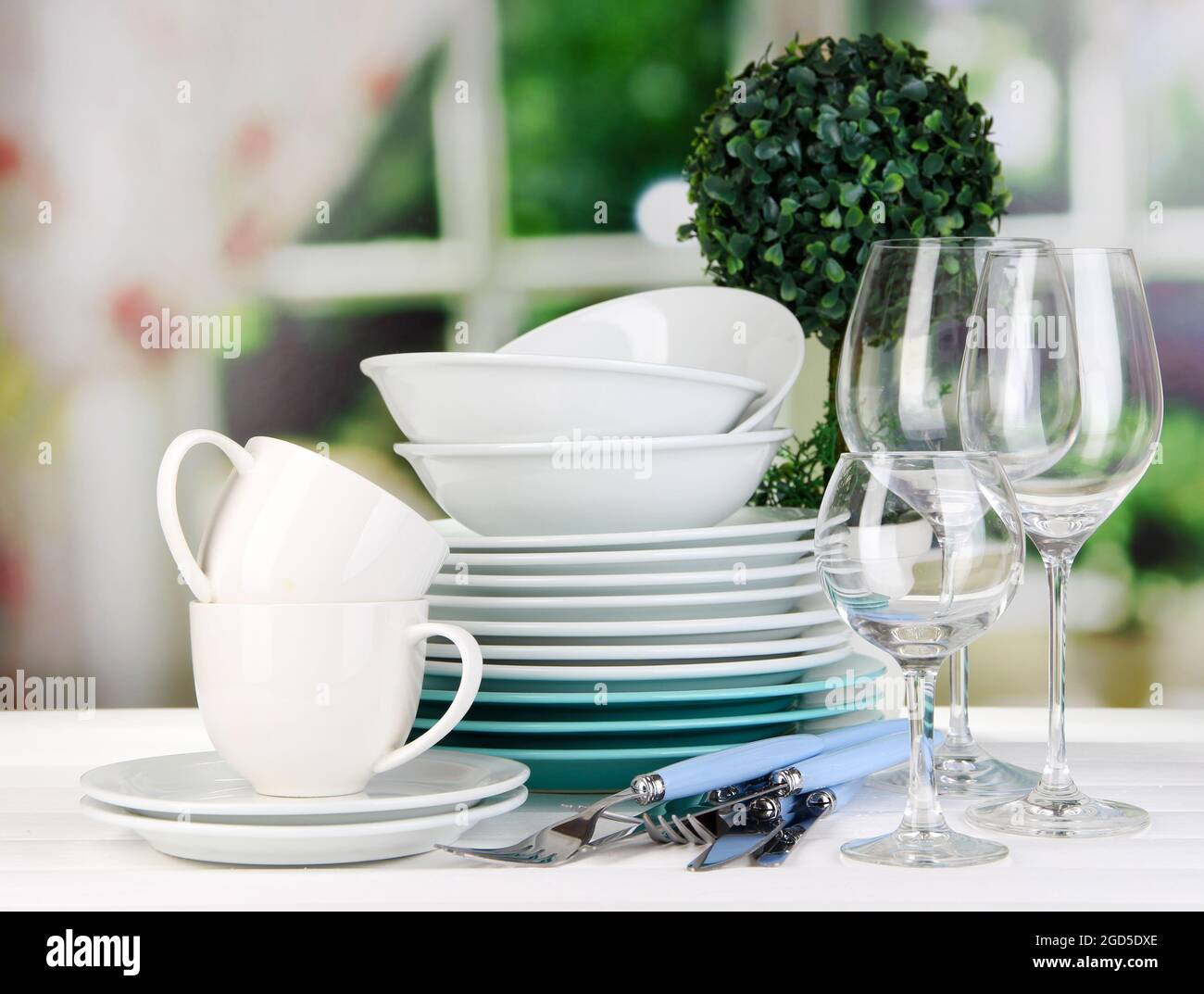 Clean dishes on table on window background Stock Photo - Alamy