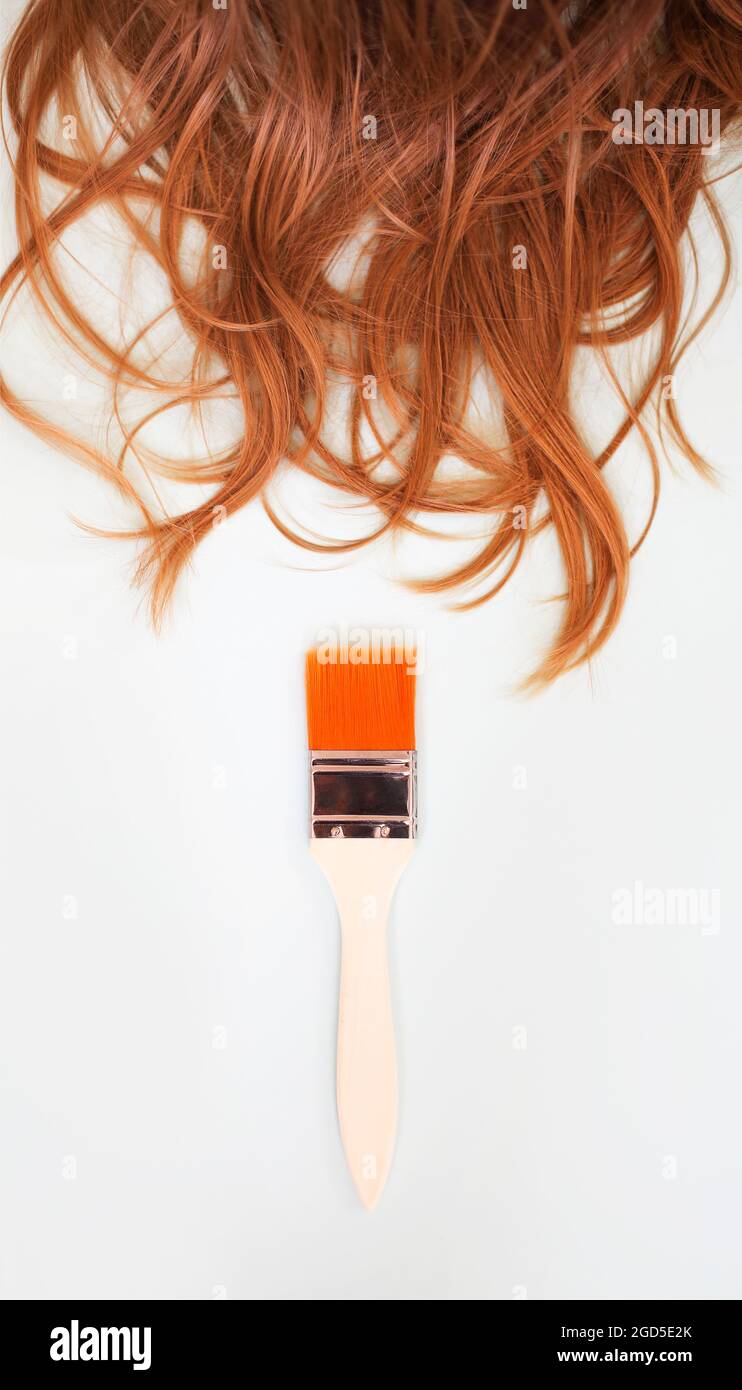 Cropped shot of female red hair curls and wide paint brush with wooden ...