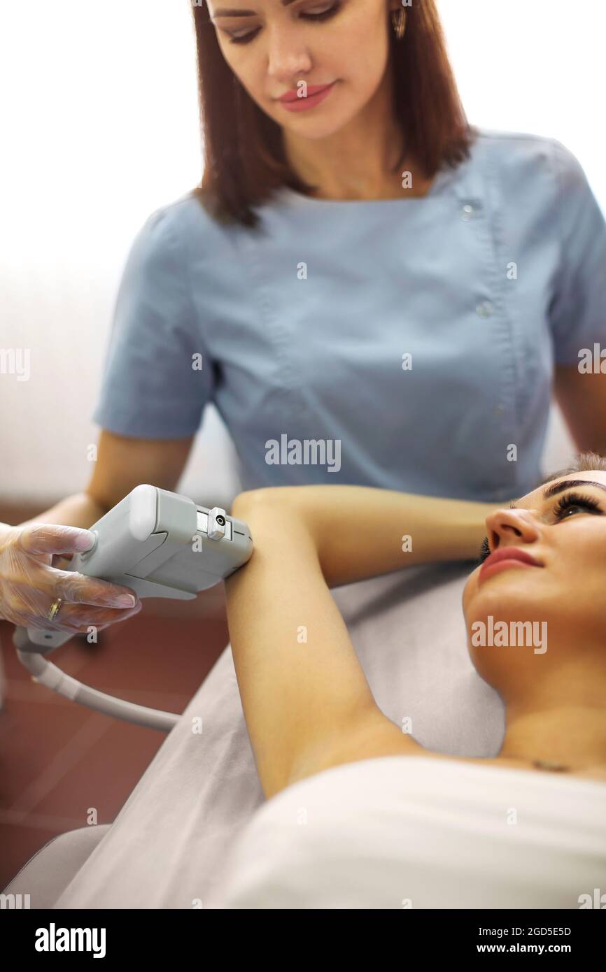 Young woman receiving photo epilation while visiting beauty center on ...