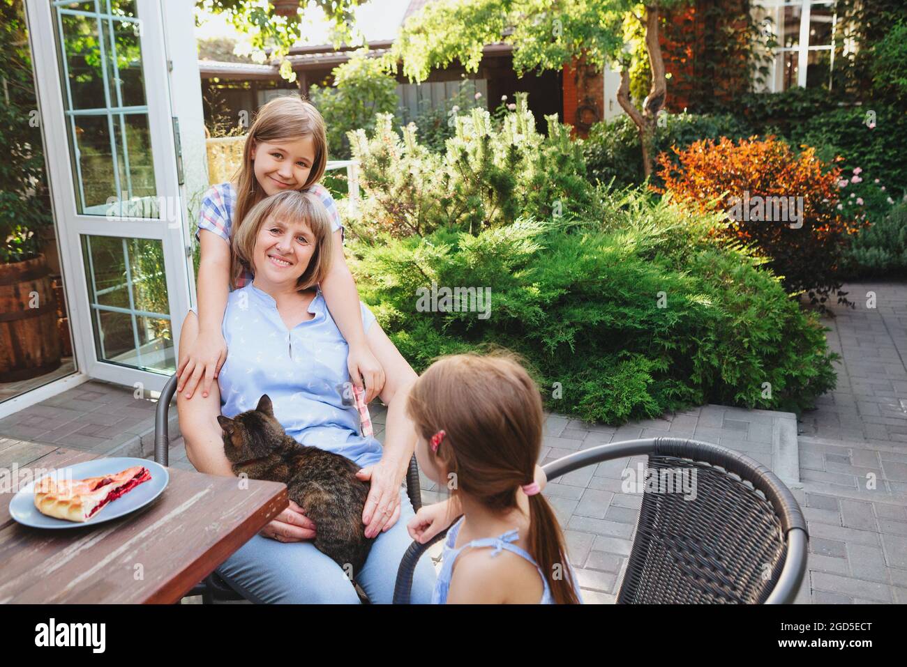 Cute little girls sitting at table and having breakfast in garden of ...