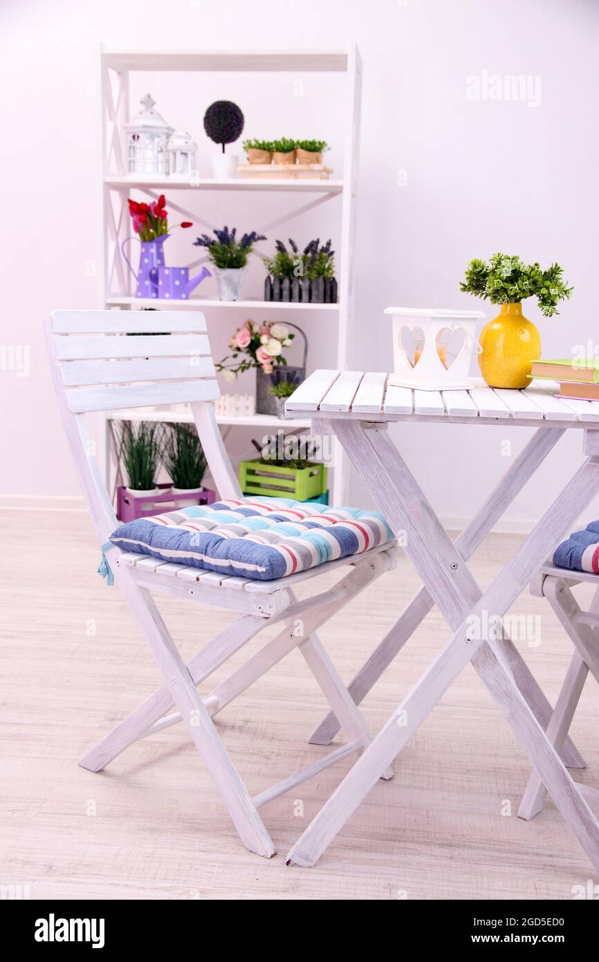 Garden chair and table with flowers on shelves on white background ...