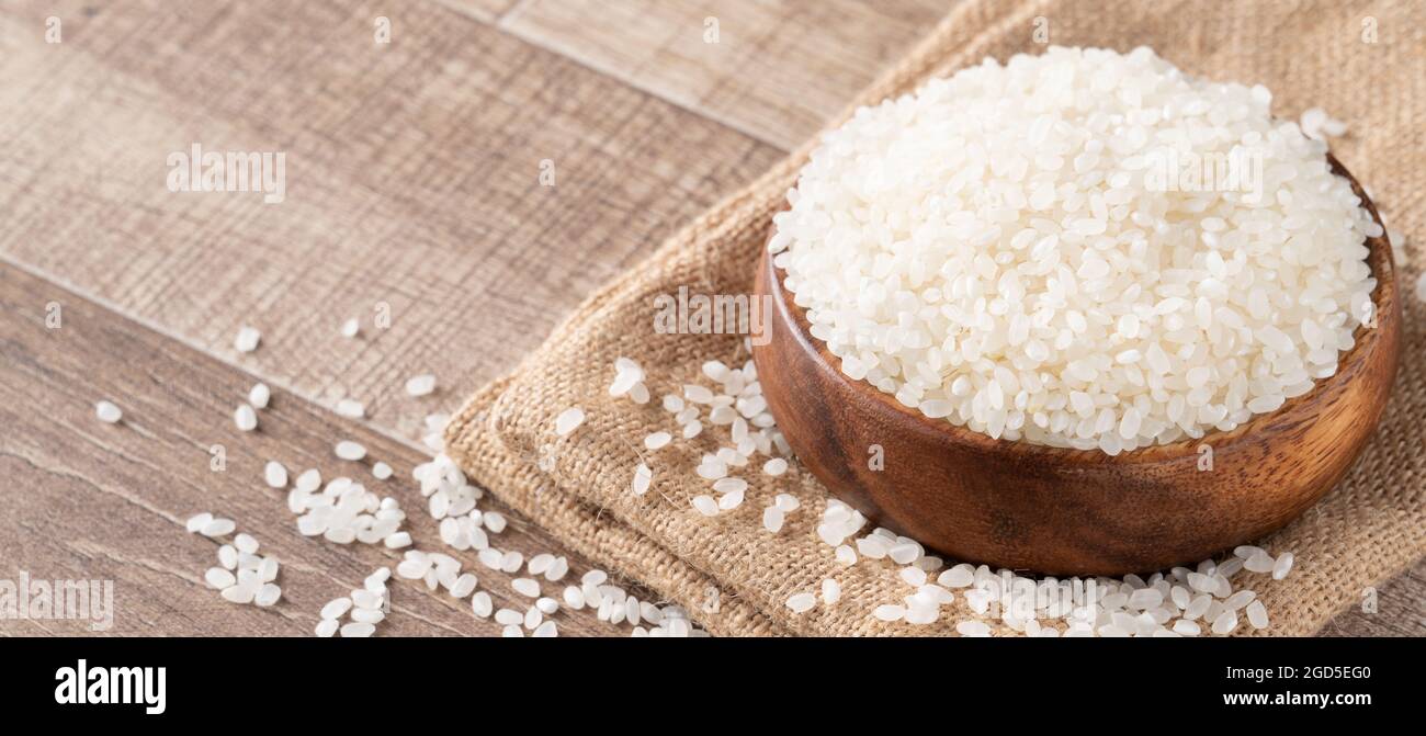 Raw white polished milled edible rice on wooden table background in a ...