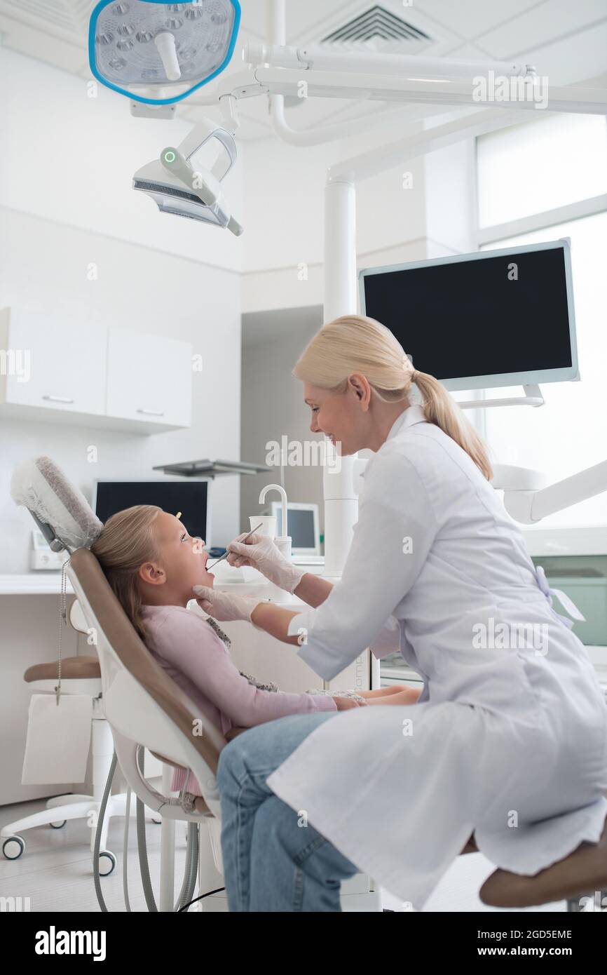 Pediadontist examining teeth of her cute small patient Stock Photo - Alamy