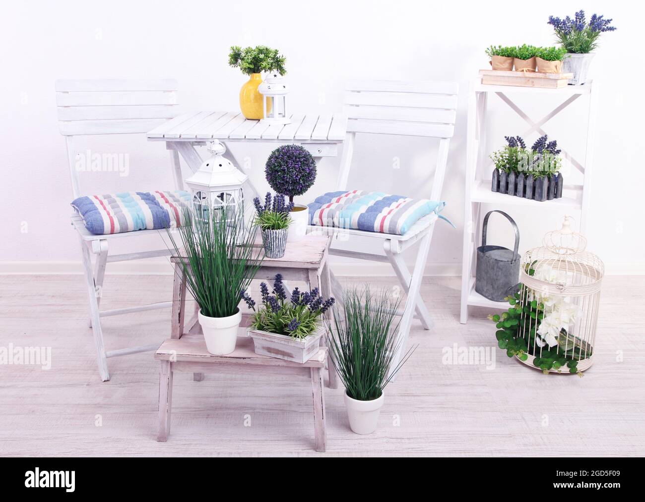 Garden chairs and table with flowers on wooden stands on white ...
