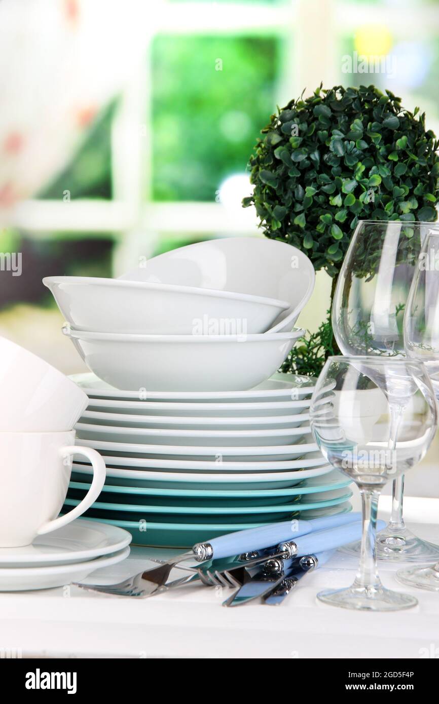 Clean dishes on table on window background Stock Photo - Alamy