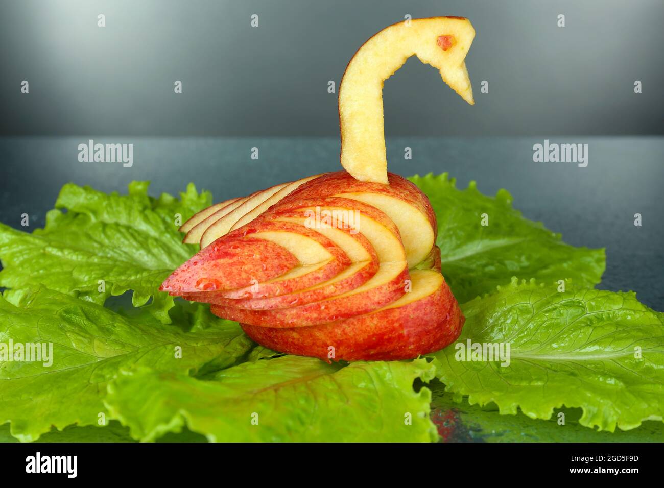 Carving fruit pattern of swan on grey wet background Stock Photo - Alamy