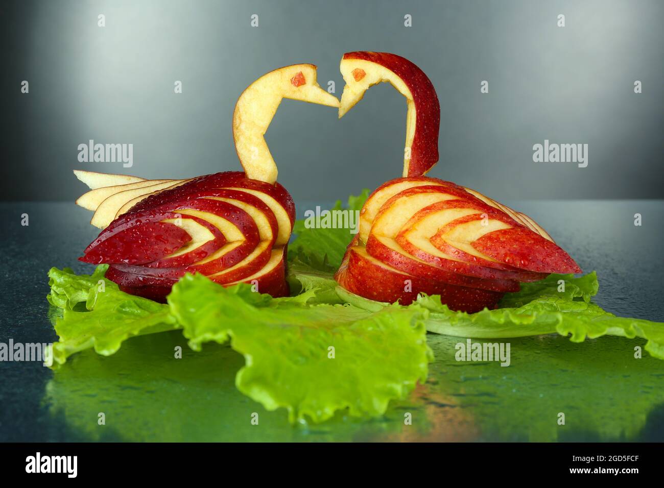 Carving fruit pattern of swan on grey wet background Stock Photo - Alamy