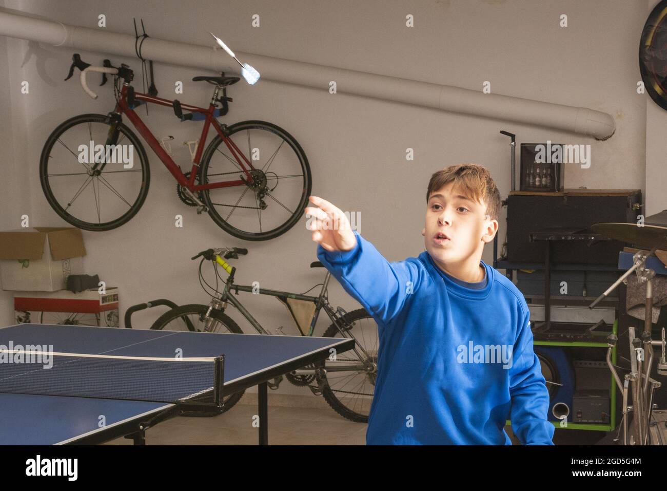Concentrated Caucasian teenager playing darts in the recreation room ...