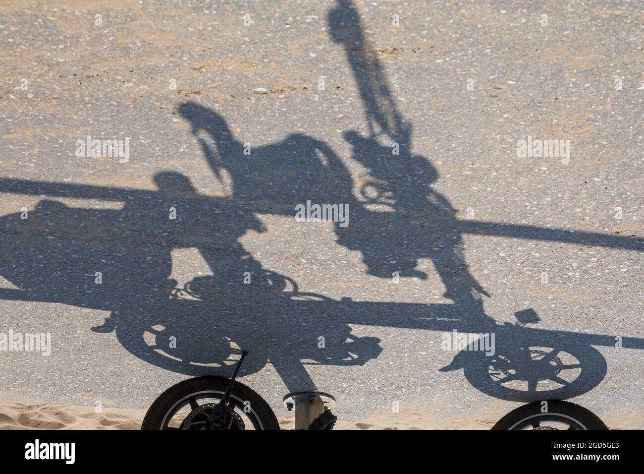 Inverted shadow of Electric bike parked on promenade at beach in Poole ...