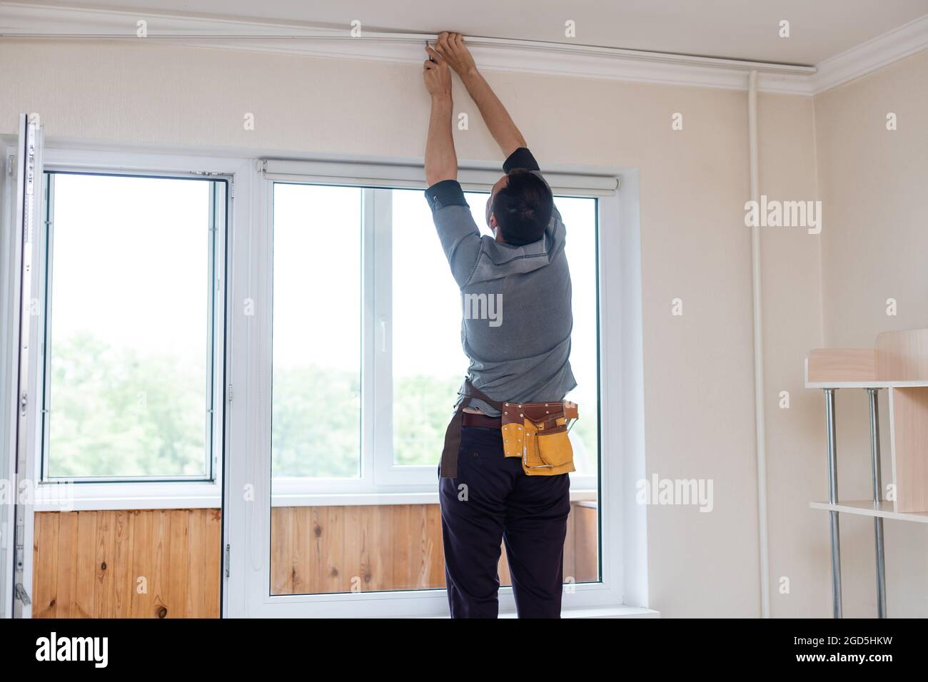 A handyman installing new cornice for curtains, home repair and ...