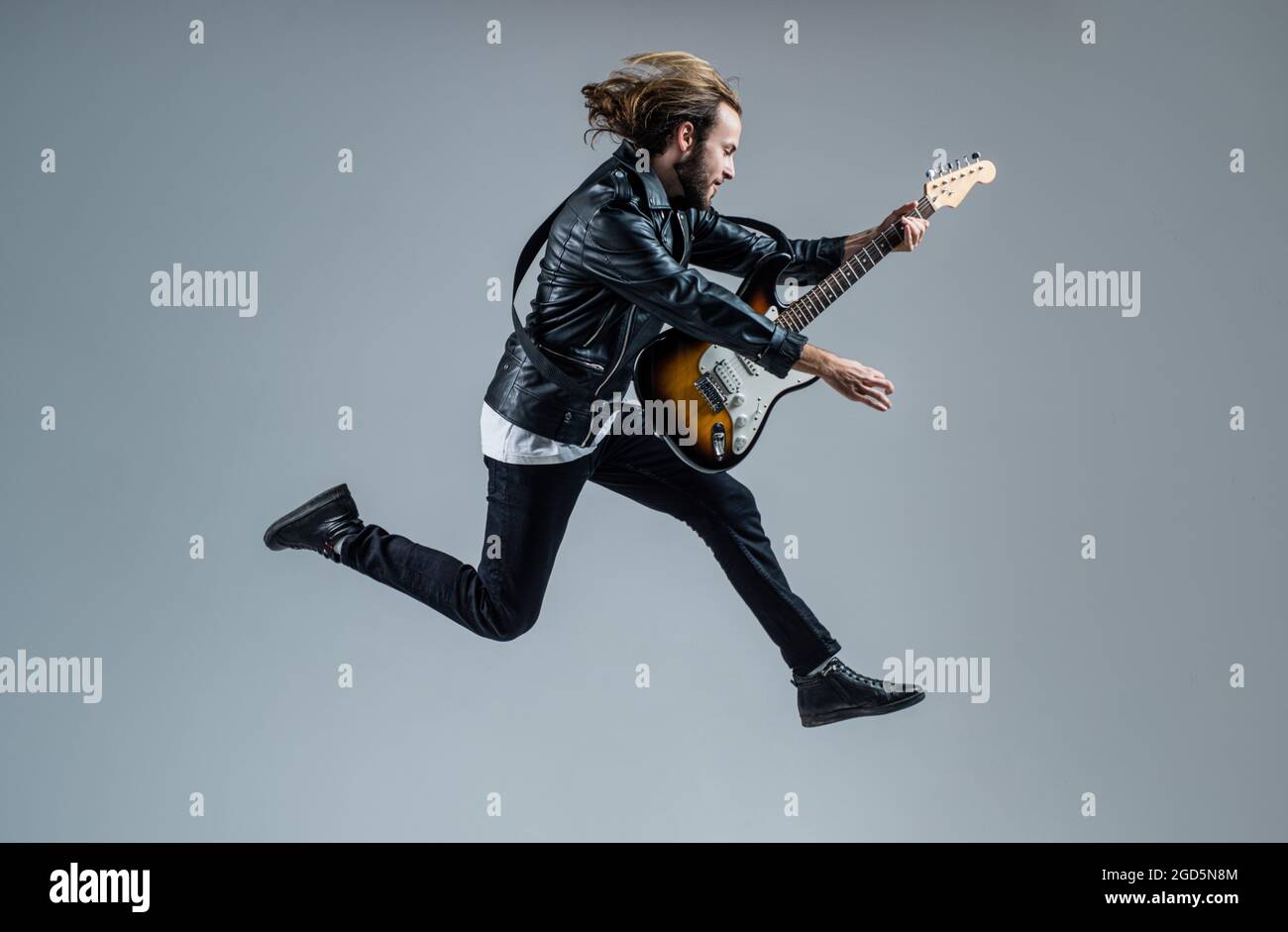 emotional bearded rock musician playing electric guitar in leather ...