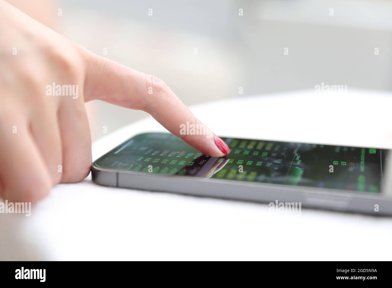 Female hand with smartphone trading stocks online in coffee shop ...