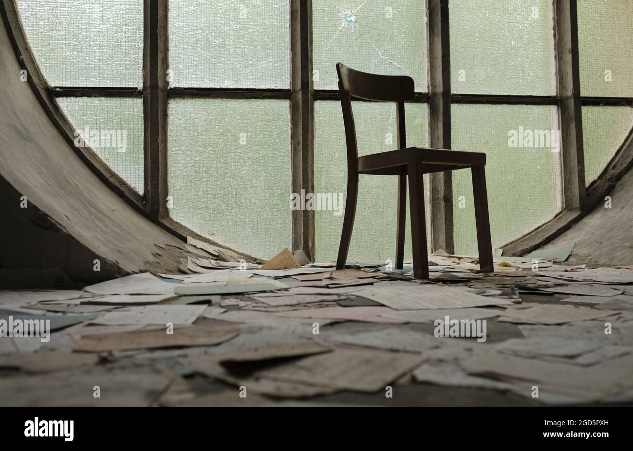 Closeup shot of a chair in front of a round window with papers and book ...