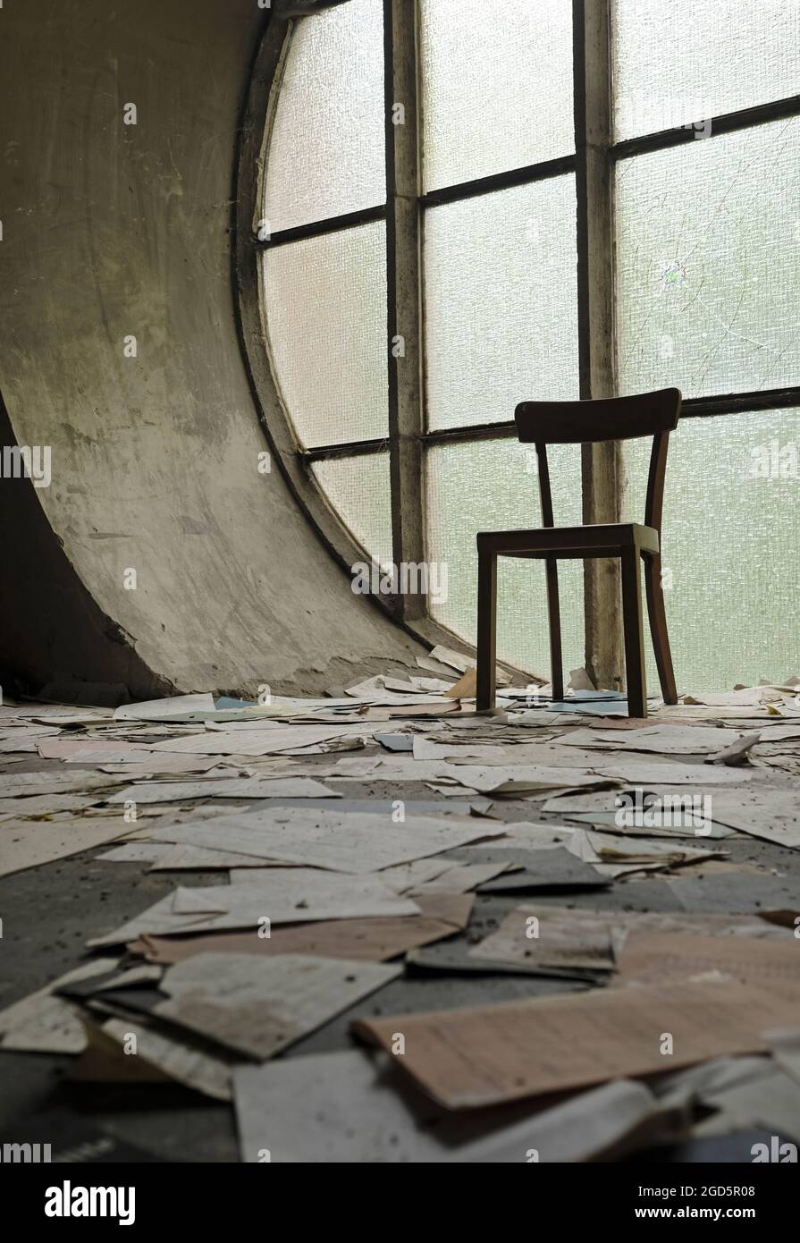 Vertical shot of a chair in front of a round window with papers and ...
