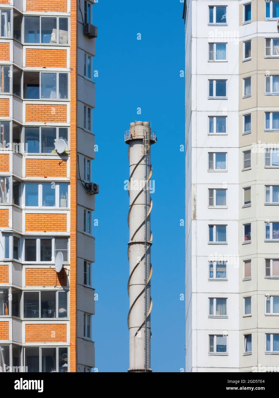 Chimney tube against a blue sky surrounded by apartment buildings Stock ...