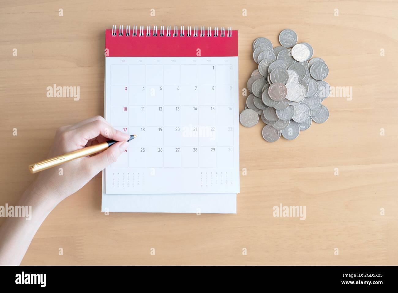 Hand writing in calendar plan and coins concept Stock Photo - Alamy