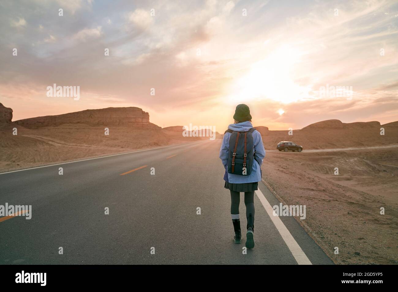 rear view of woman traveler walking on highway in gobi desert with ...