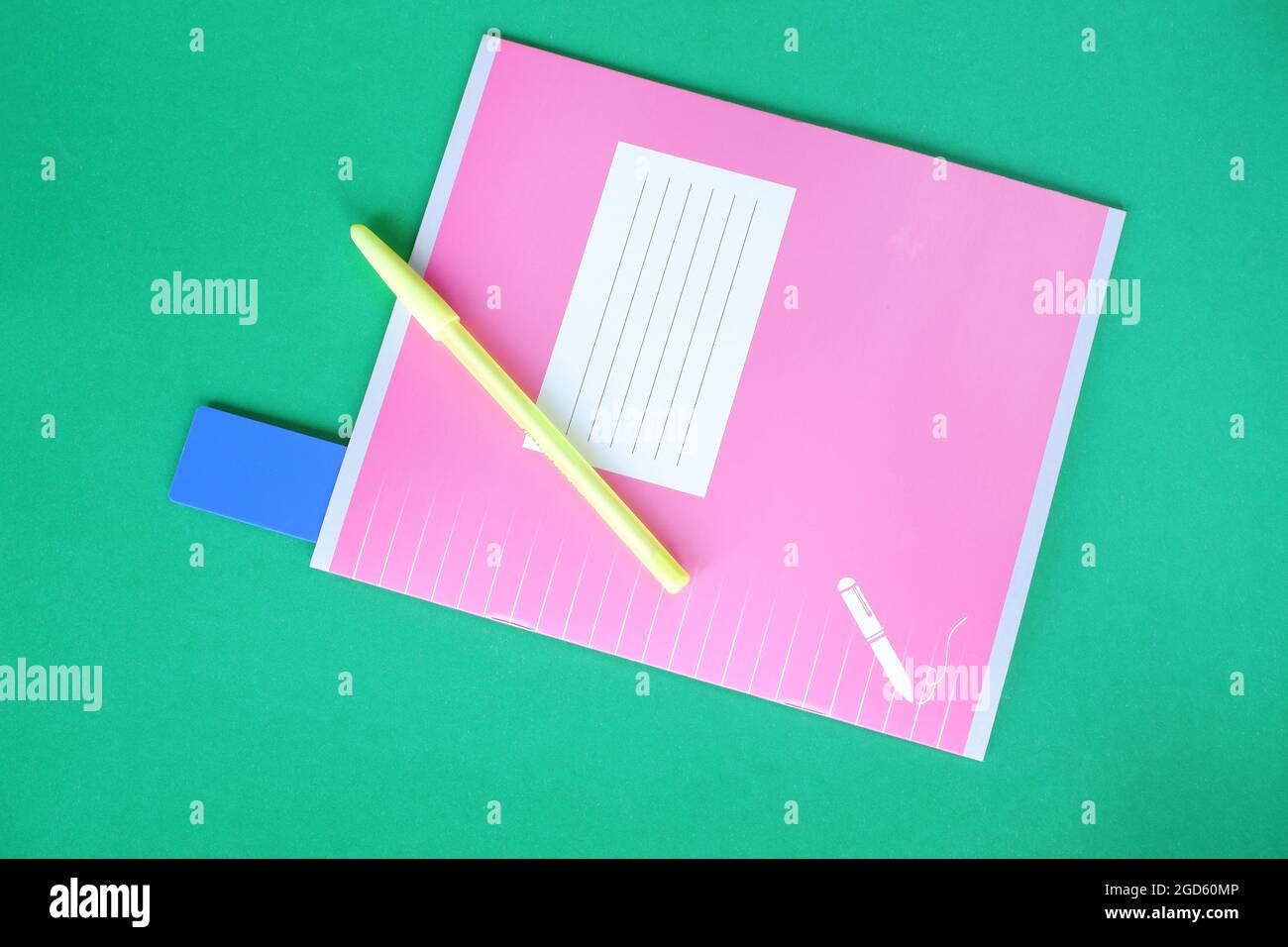 Pink notebook with stationery accessories on a green background. 1 ...
