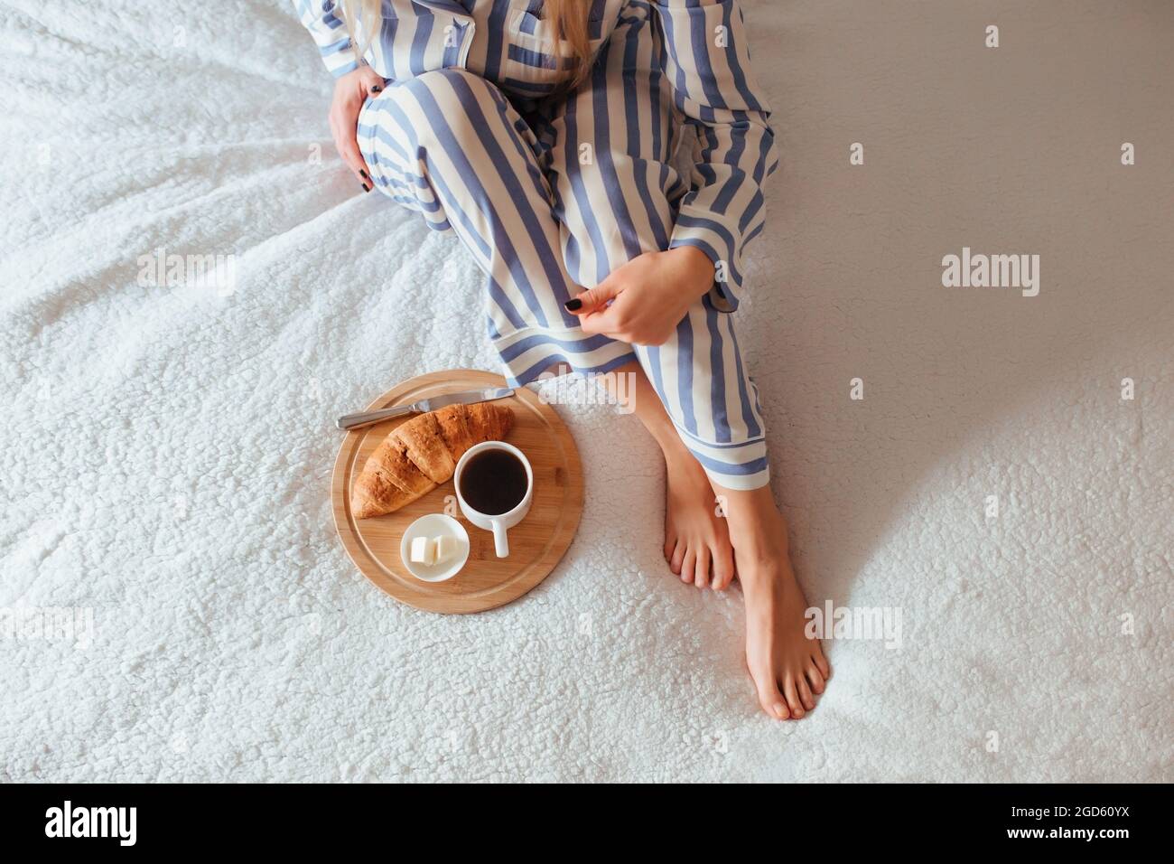 women's beautiful legs in pyjamas and next to a coffee with a croissant ...
