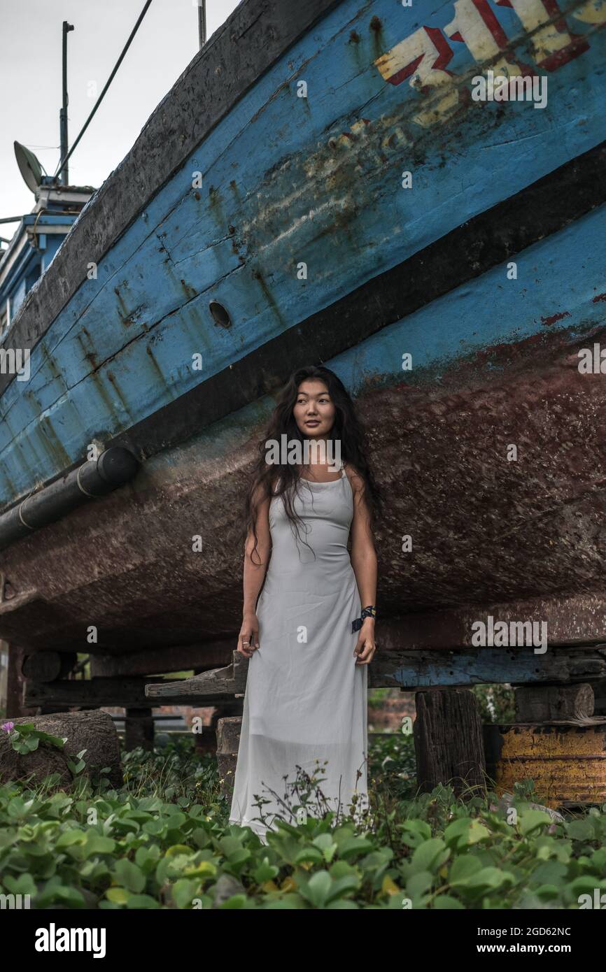 Beautiful young mongol woman in white dress standing near old wooden ...