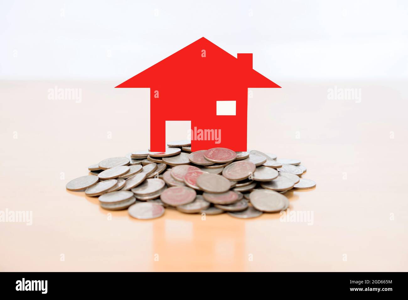 Red house sitting on a stack coins Stock Photo - Alamy