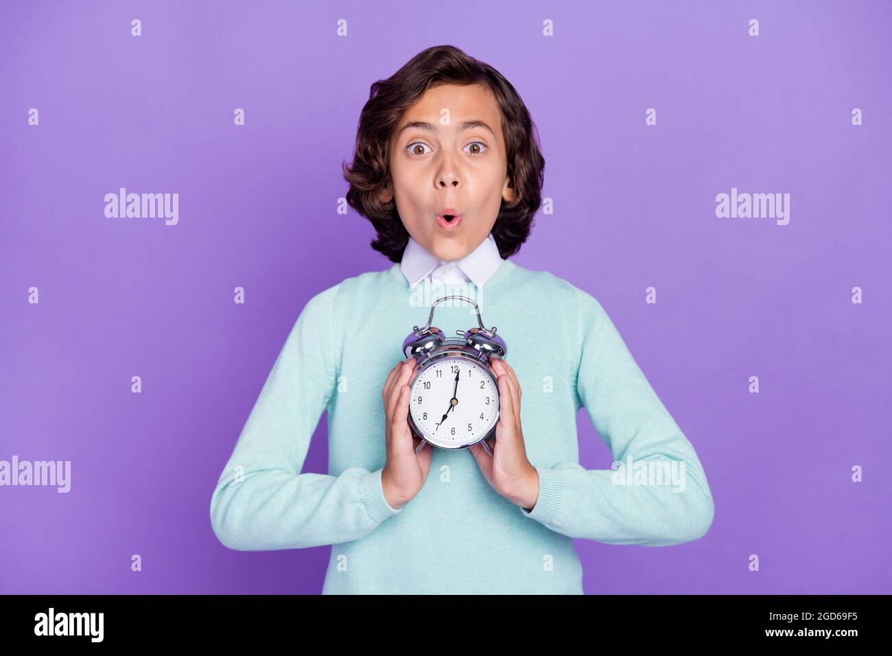 Photo of little impressed brunet boy hold clock wear blue sweater ...