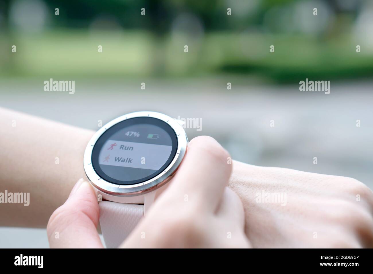 Woman running outdoors using watch Stock Photo - Alamy