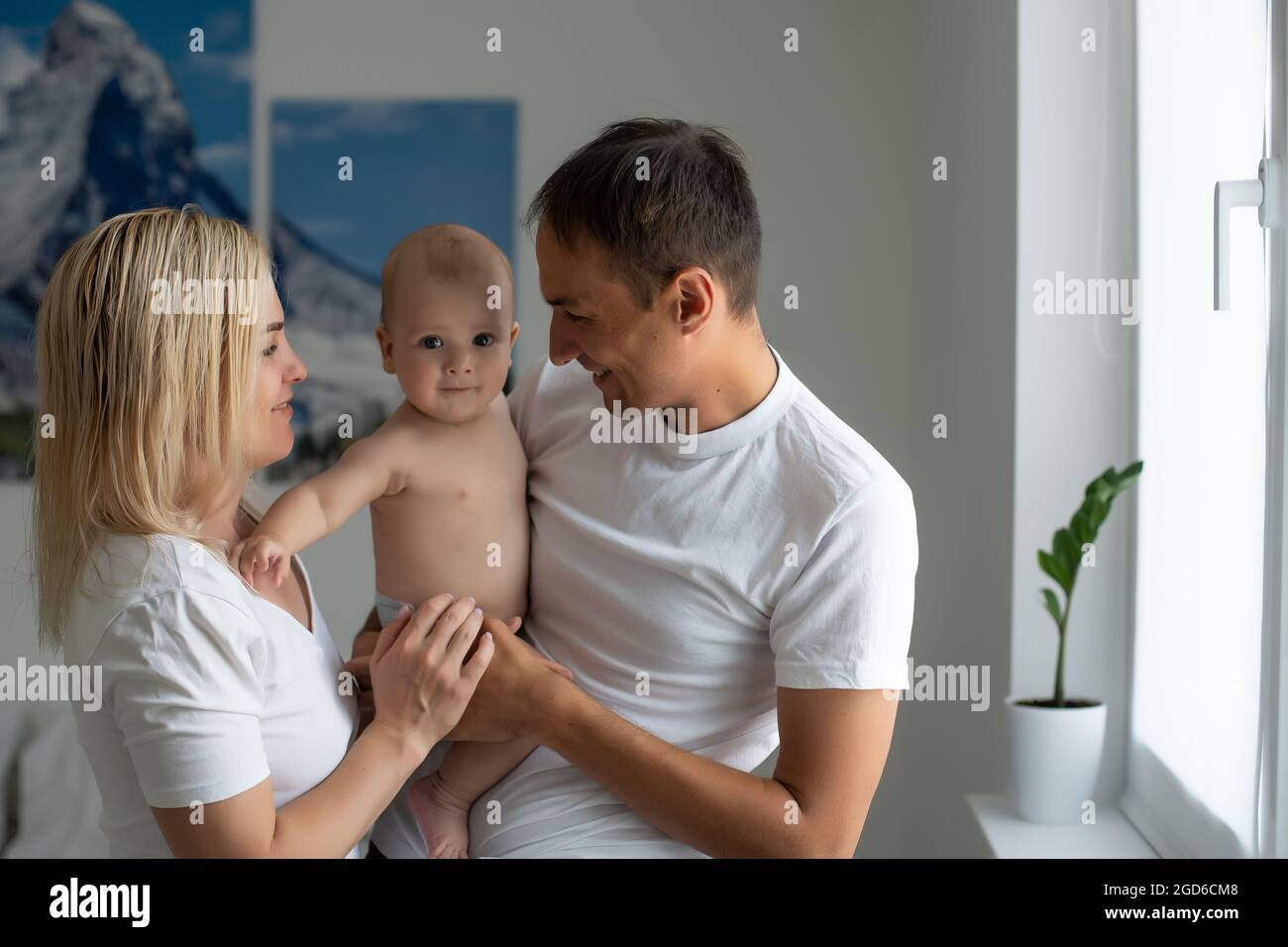 middle-aged parents with baby in white bedroom Stock Photo - Alamy