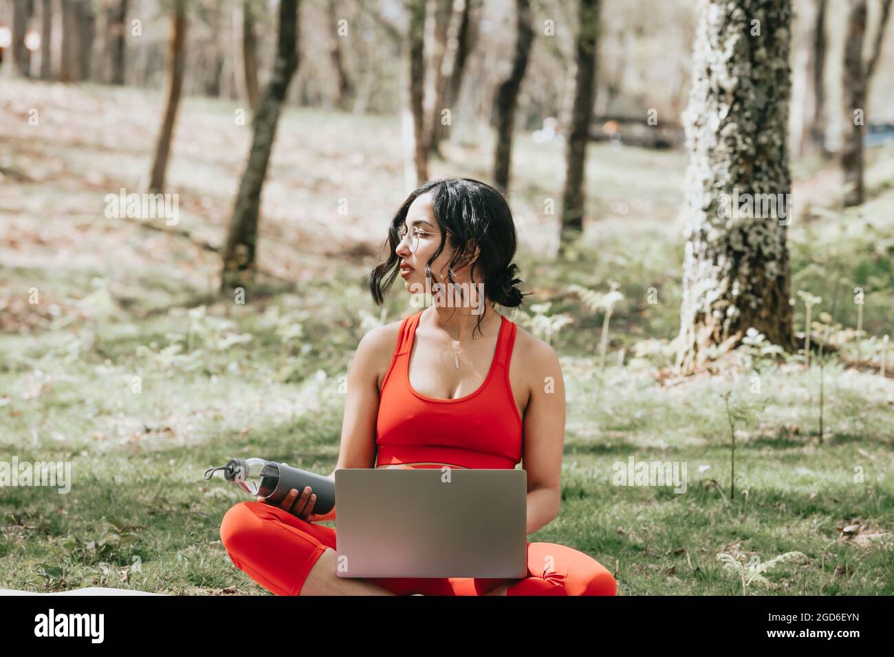 Middle Eastern female in yoga clothes sitting in the middle of a park ...