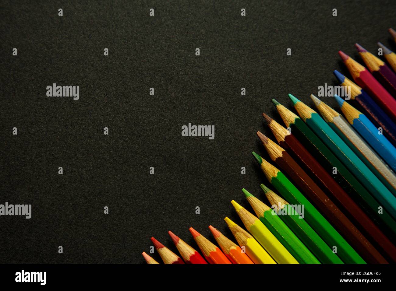Overhead shot of a row of color pencils on black background with space ...