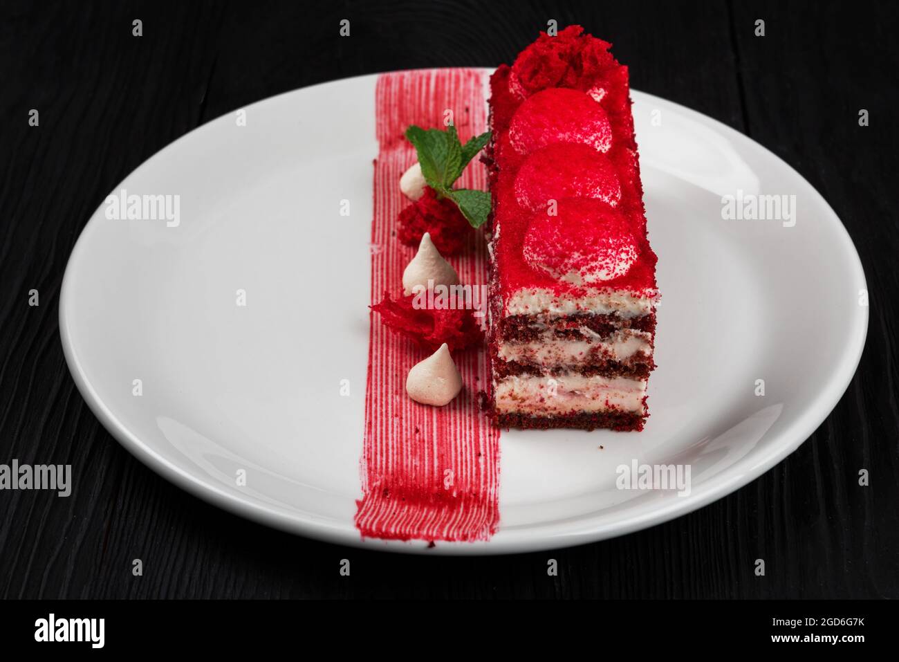 Plate with piece of delicious red velvet cake on black wooden ...