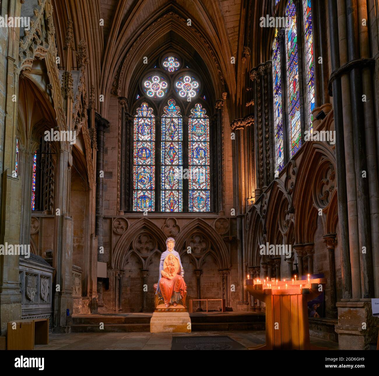 Statue of Mary and Jesus alongside a stand of lighted candles in the ...
