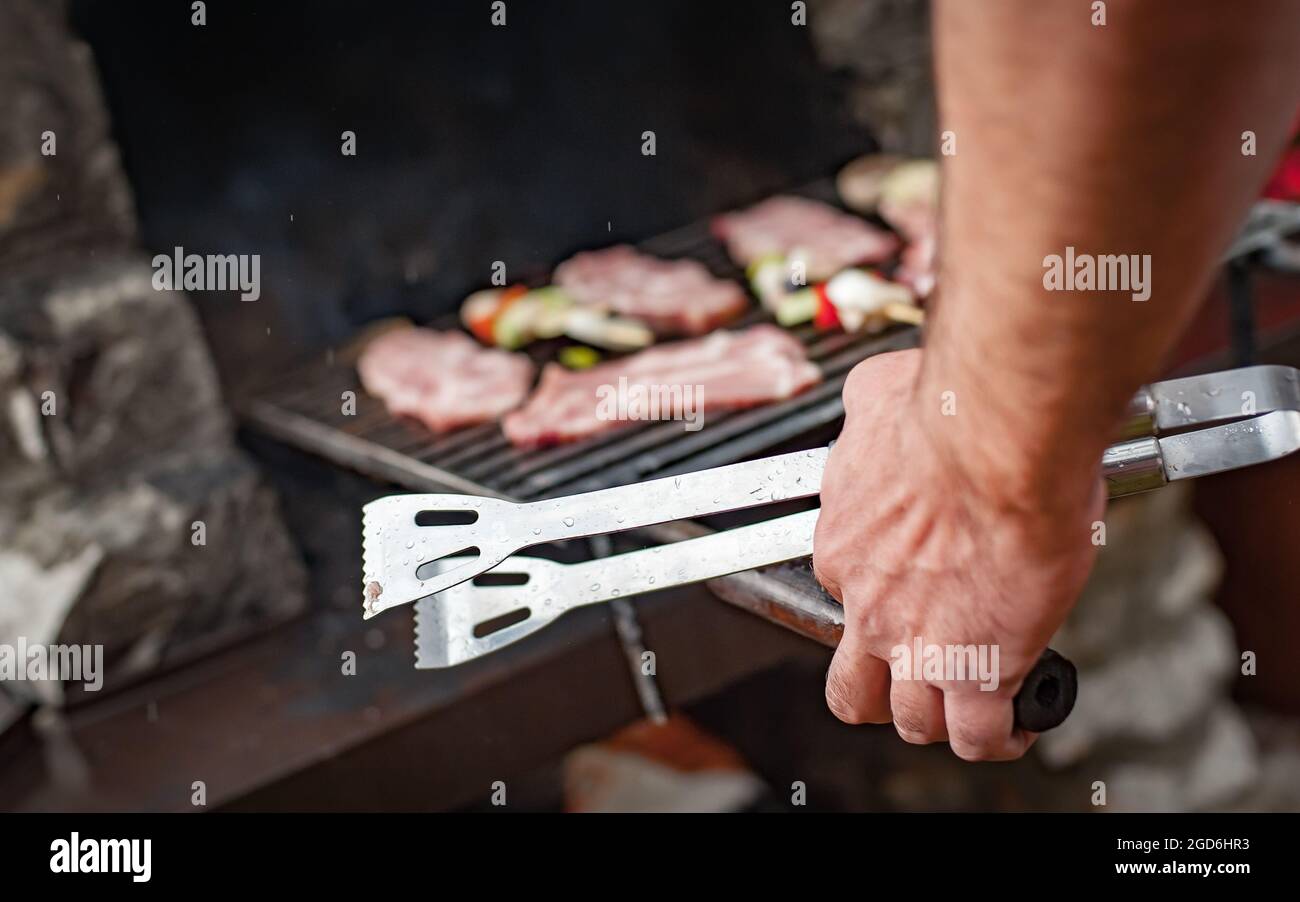 Man cooking meat on barbecue grill at bbq party in summer garden. Food ...