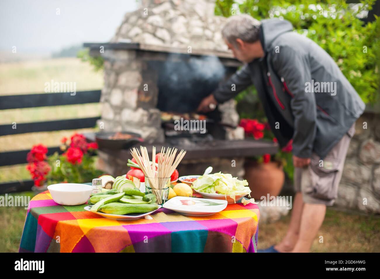 BBQ grilling party. The host man putting meat on the grill while ...