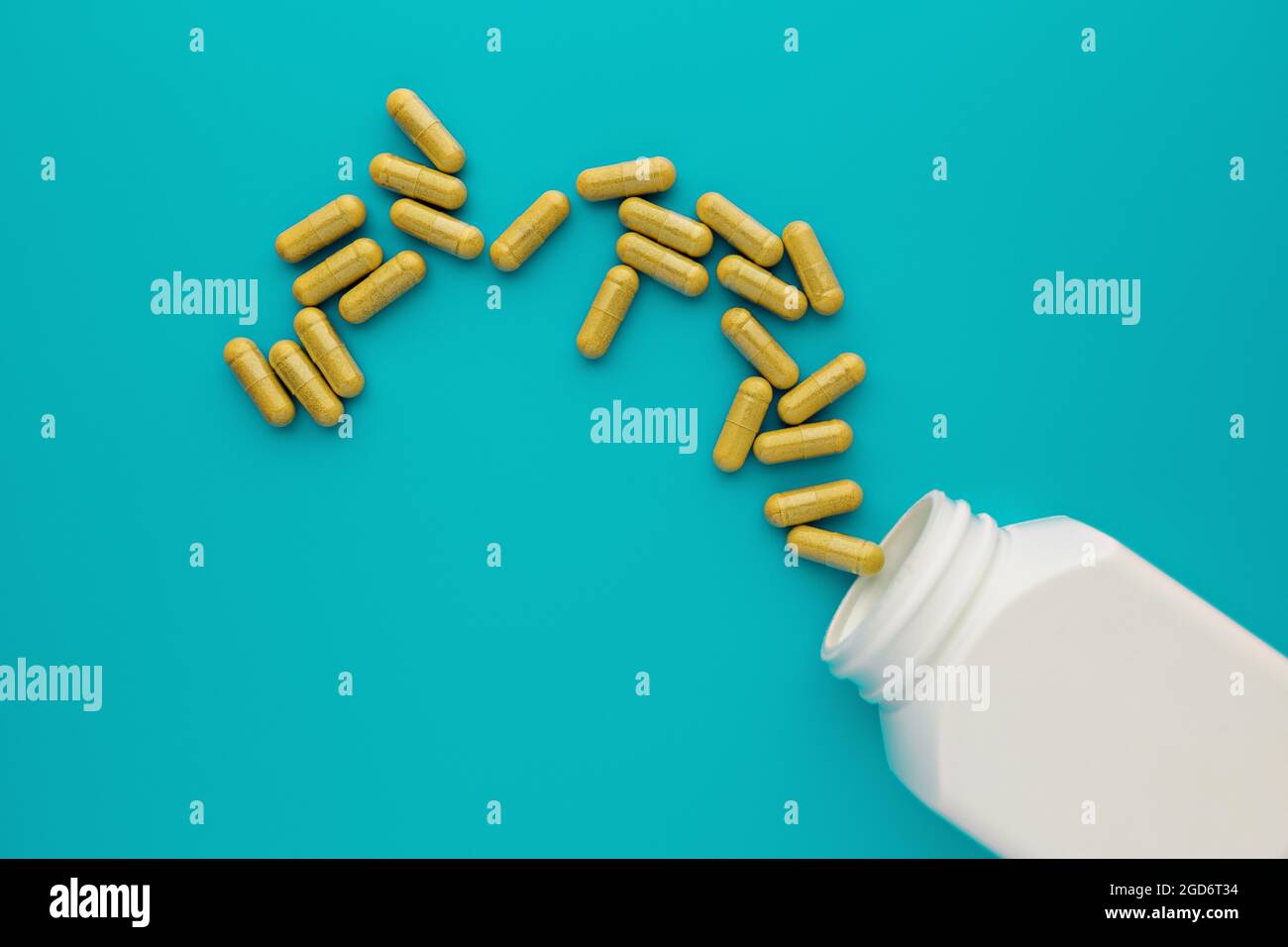 yellow dietary supplement capsules poured out of the white unbranded ...