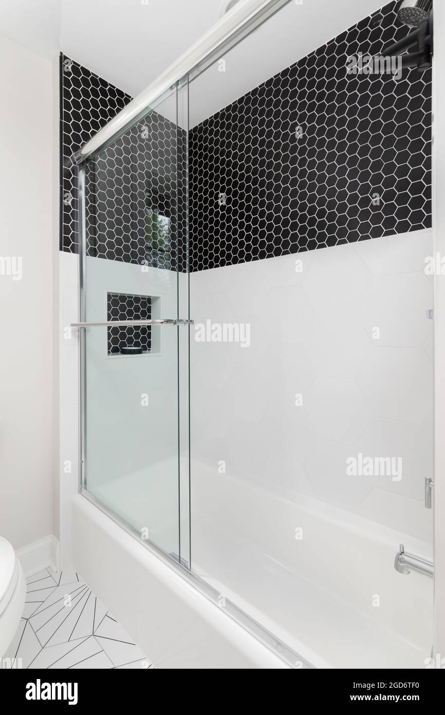 A shower with small black hexagon and large white hexagon tiles in a ...