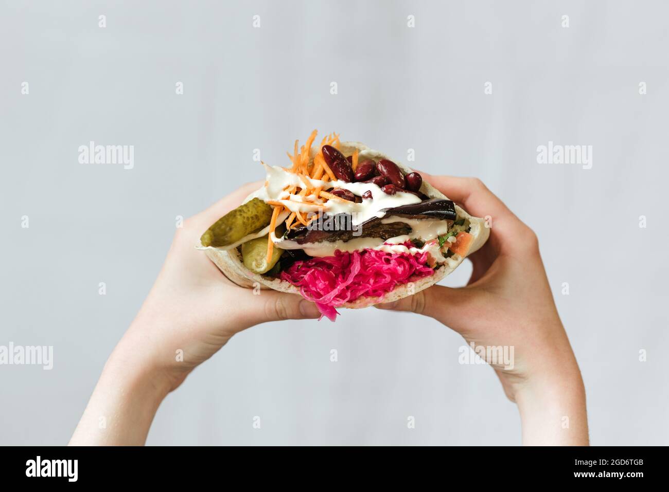 Closeup shot of hands holding vegetarian shawarma with red beans, and ...