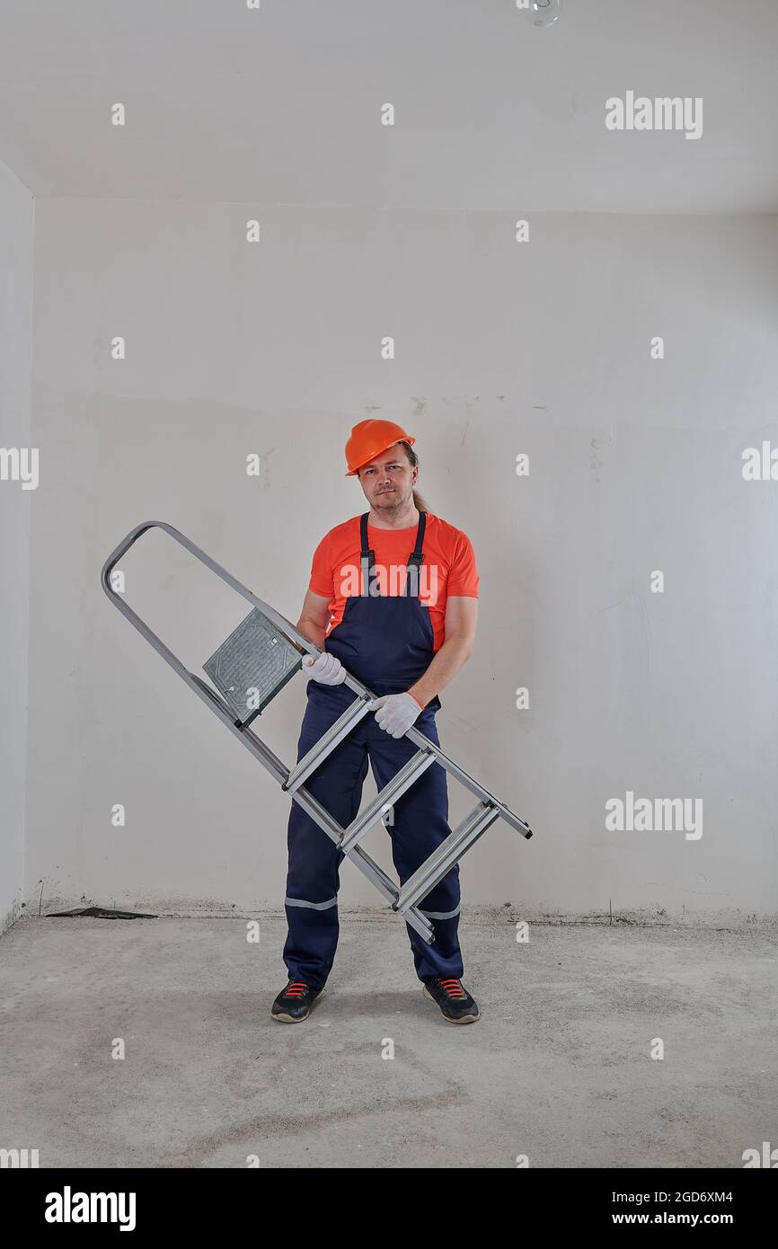 cheerful pumped up repairman holds a ladder above his head Stock Photo ...
