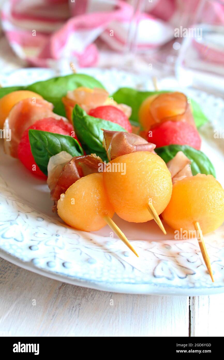 Healthy snack melon, watermelon, raw ham and basil on white background ...