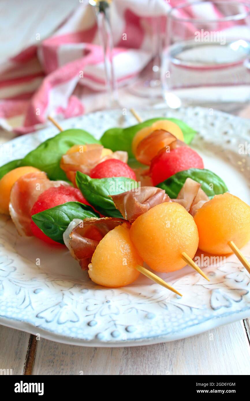 Healthy snack melon, watermelon, raw ham and basil on white background ...