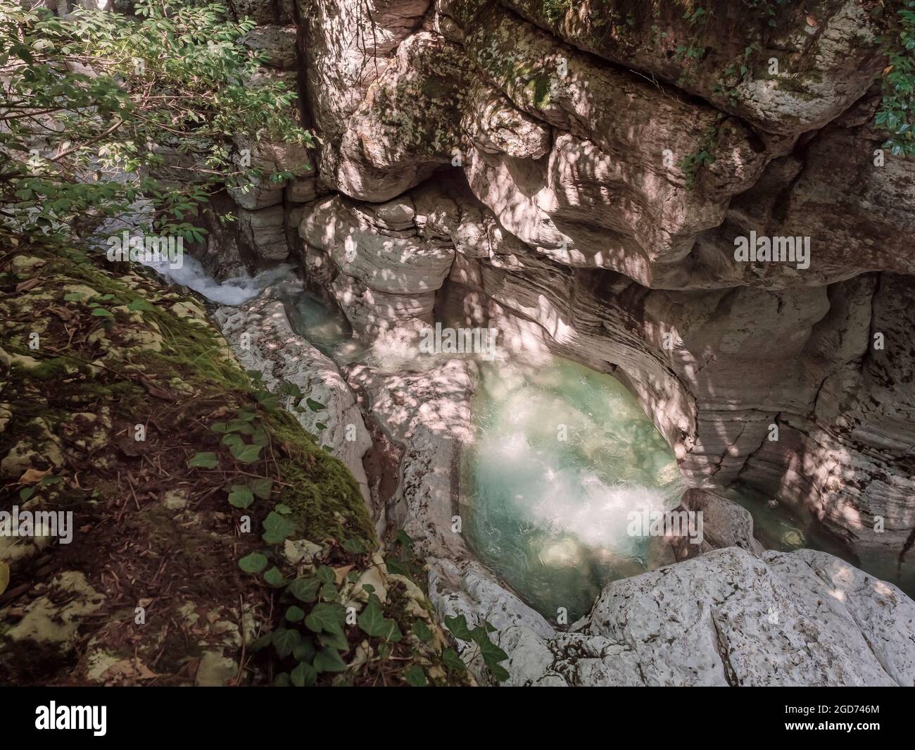 A seething clear river flowing into gorge between relief canyons ...