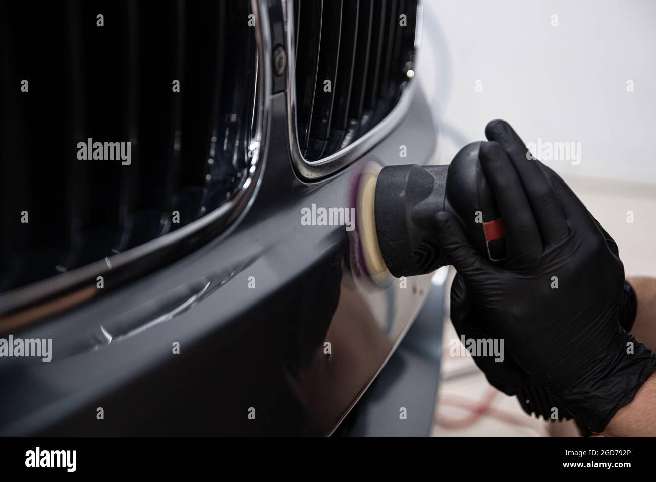 Car detailing studio worker polishing car paint Stock Photo - Alamy