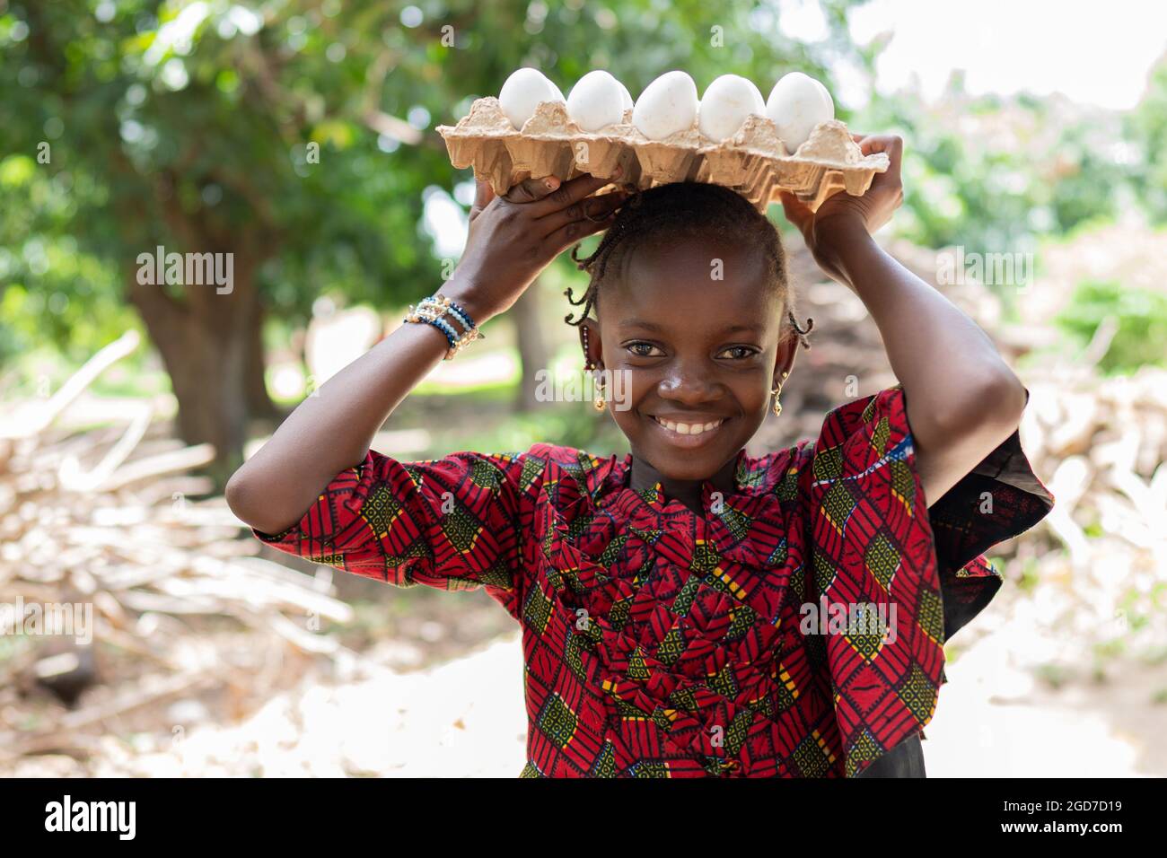 In this image, a pretty little African girl with earrings and bangles ...