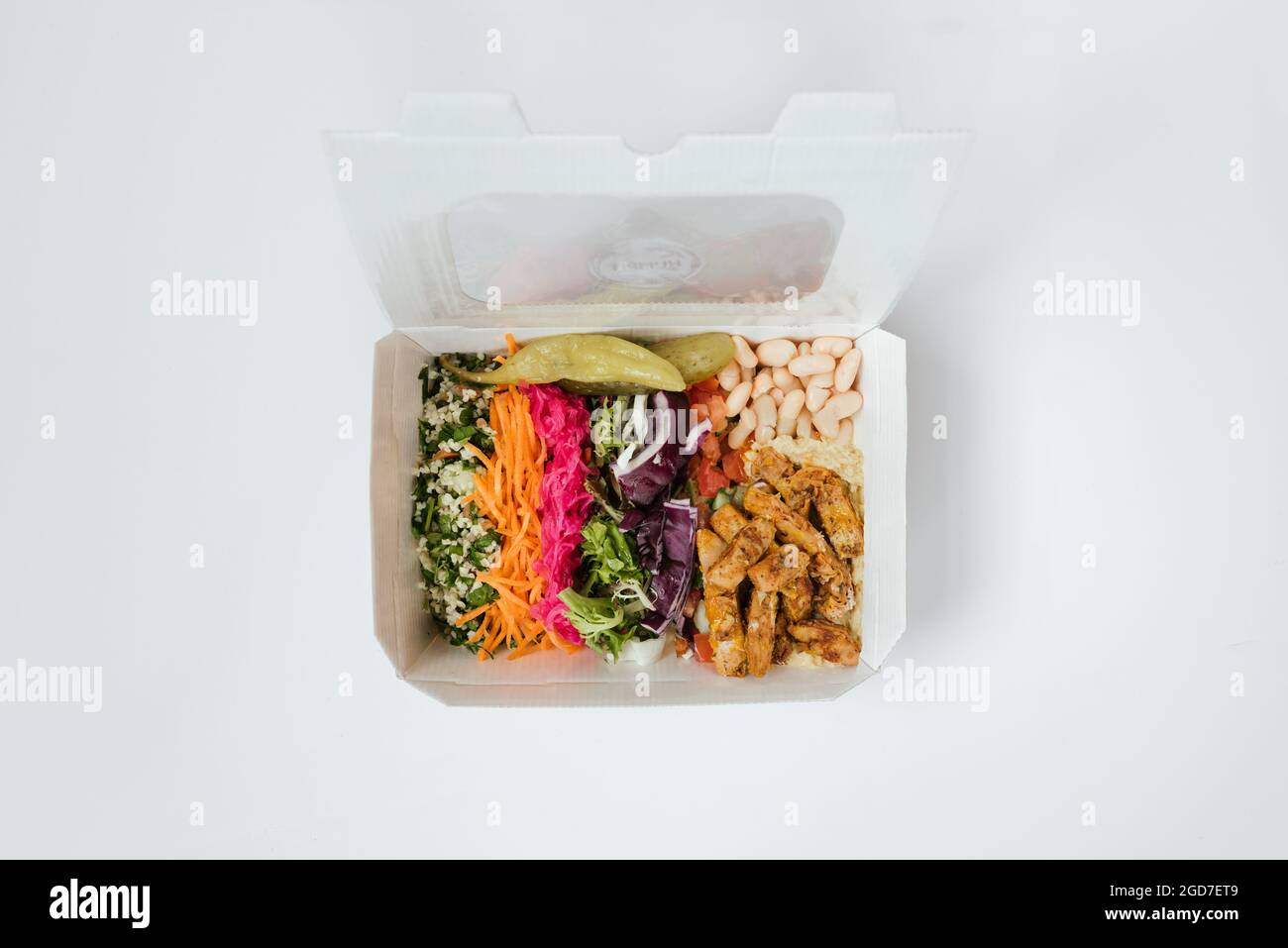 Top view shot of the lunch box with chicken sticks, hummus, and salads ...