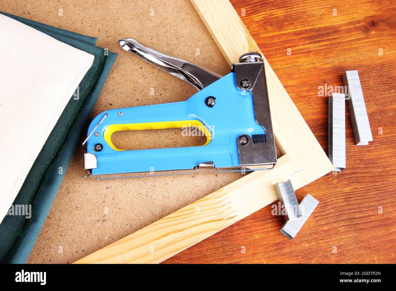 Construction stapler with fabrics and staples on cork board on wooden ...