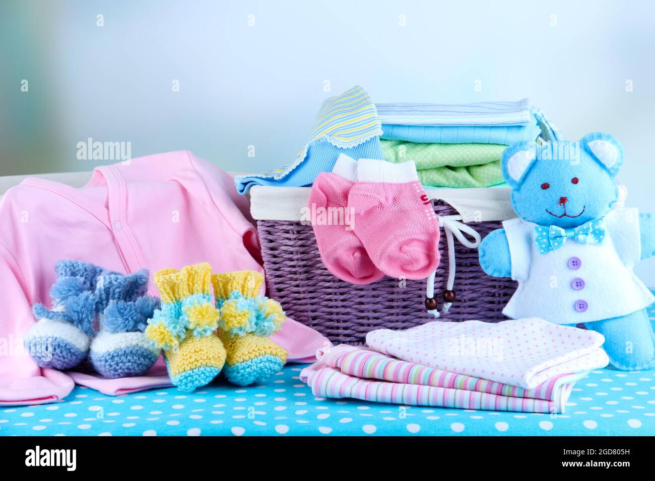 Pile of baby clothes in basket, on table on color background Stock ...