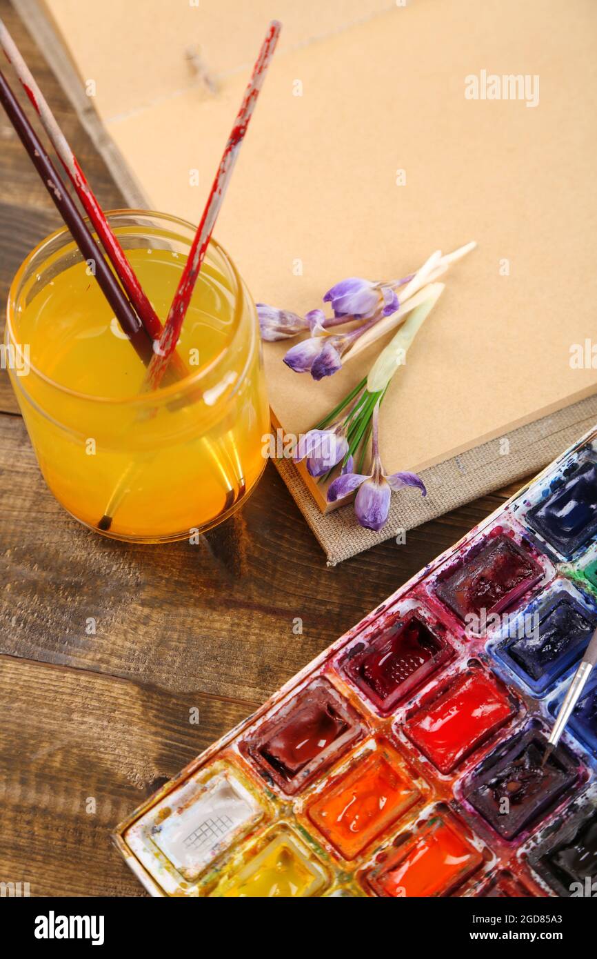 Composition with colorful watercolors, brushes and sketcher on wooden ...
