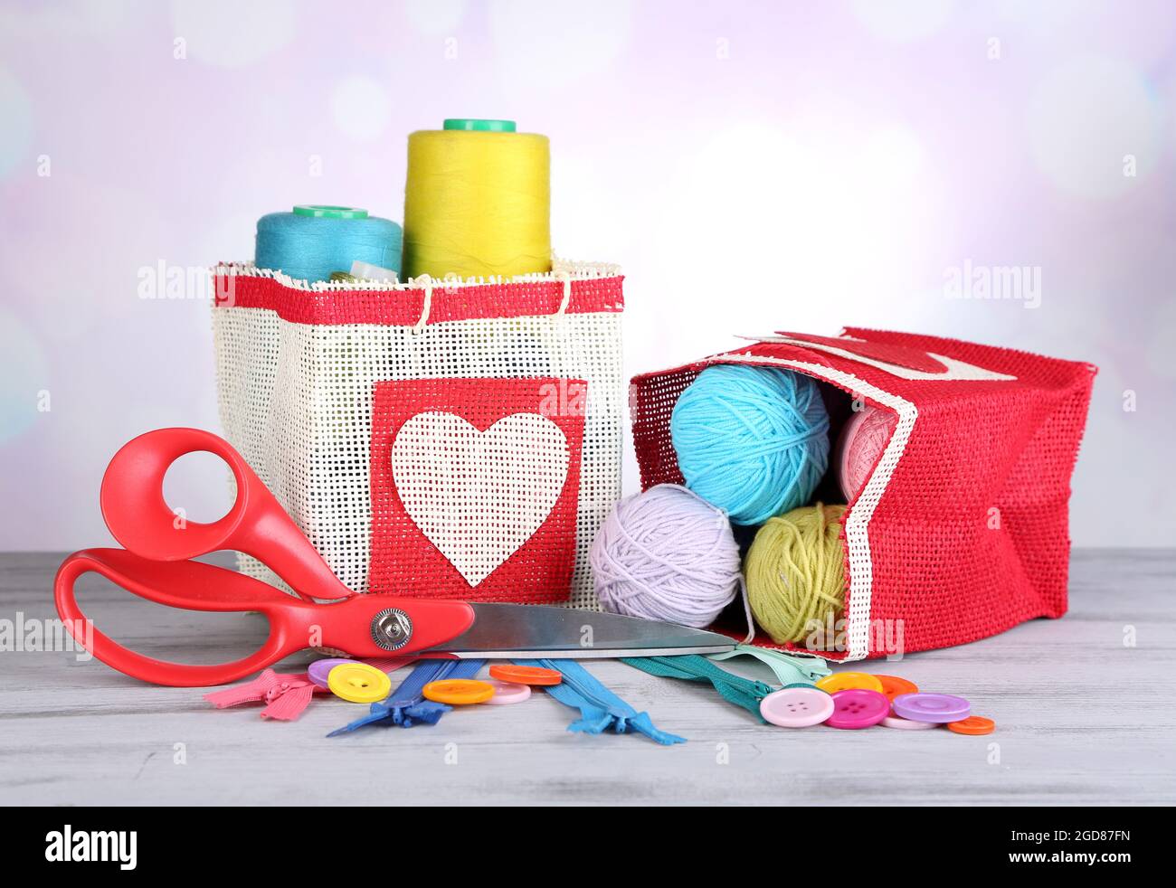 Bags with bobbins of colorful thread and woolen balls on wooden table ...