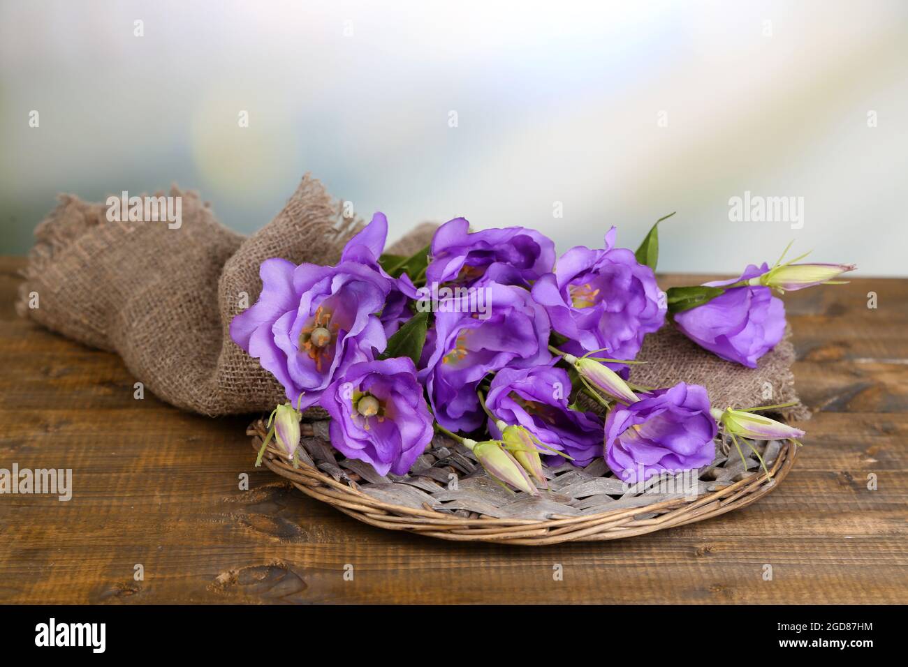Purple artificial eustoma on sackcloth on color wooden table, on bright ...