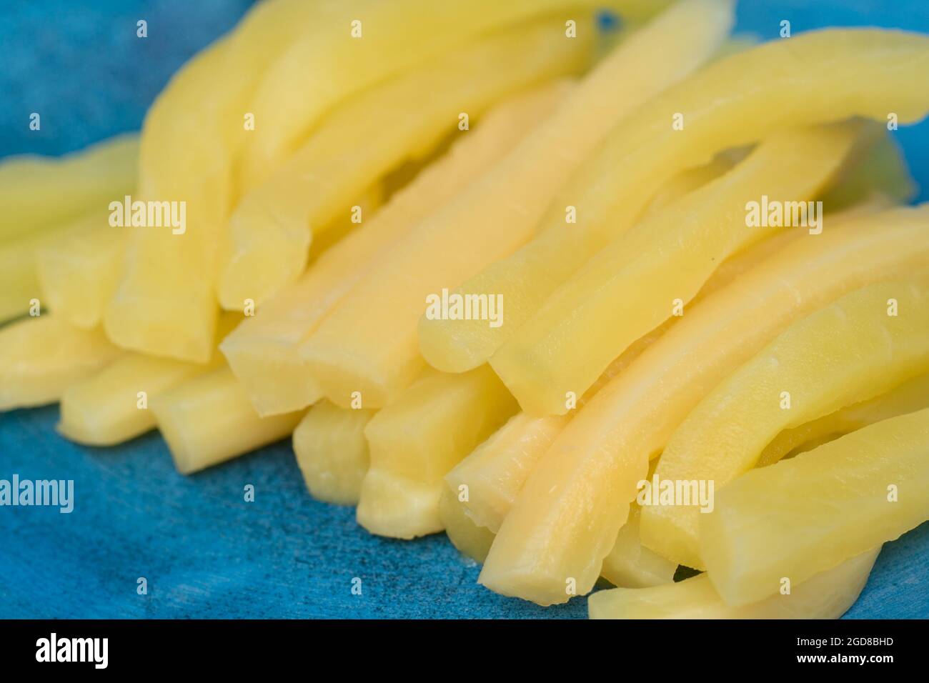 yellow marinated pieces of japanese radish, daikon on blue plate Stock ...